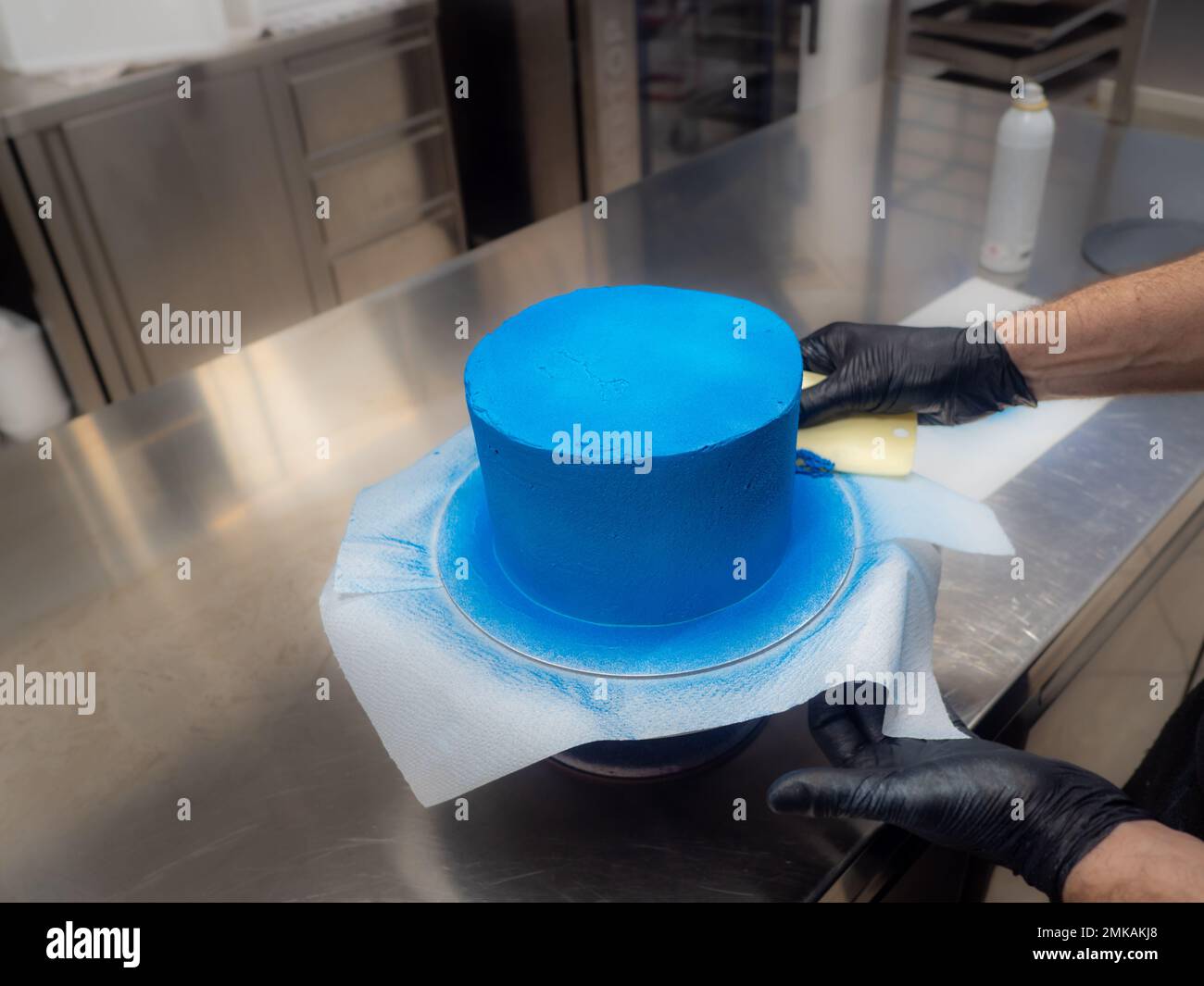 blue sprayed frosted cake on stand ready for decoration at bakery lab ...