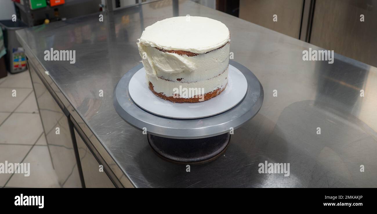 chef pastry designer confectioning a frosted 3 floor layered cake ...