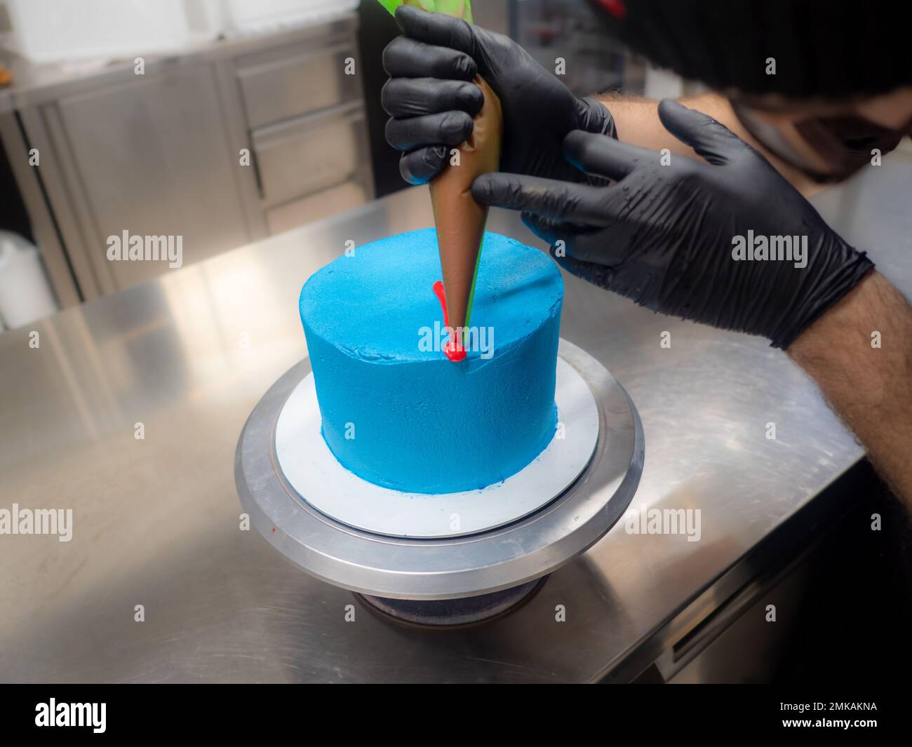 blue sprayed frosted cake on stand ready for decoration at bakery lab ...