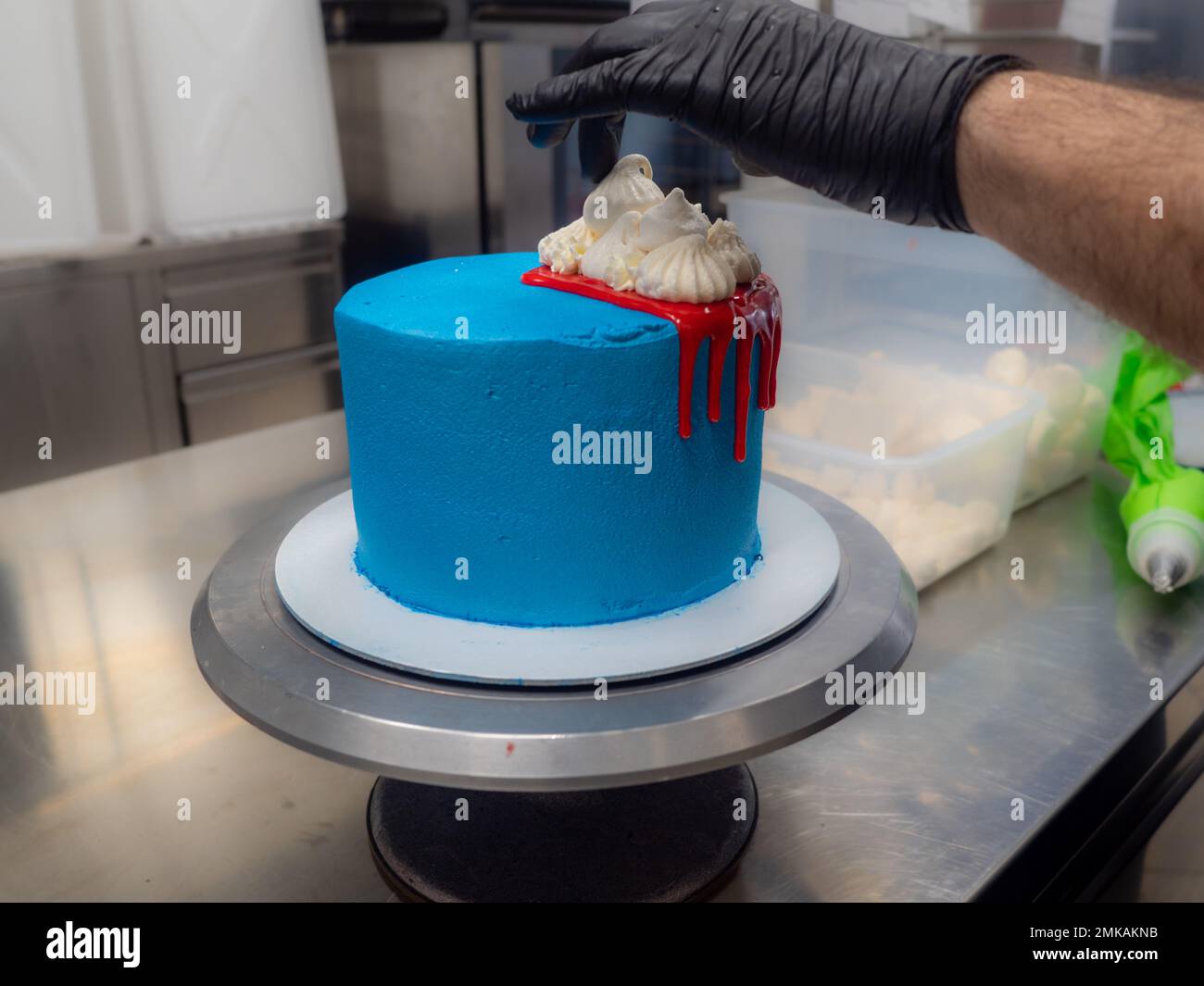 blue sprayed frosted cake on stand dripped with red ganache filling and ...