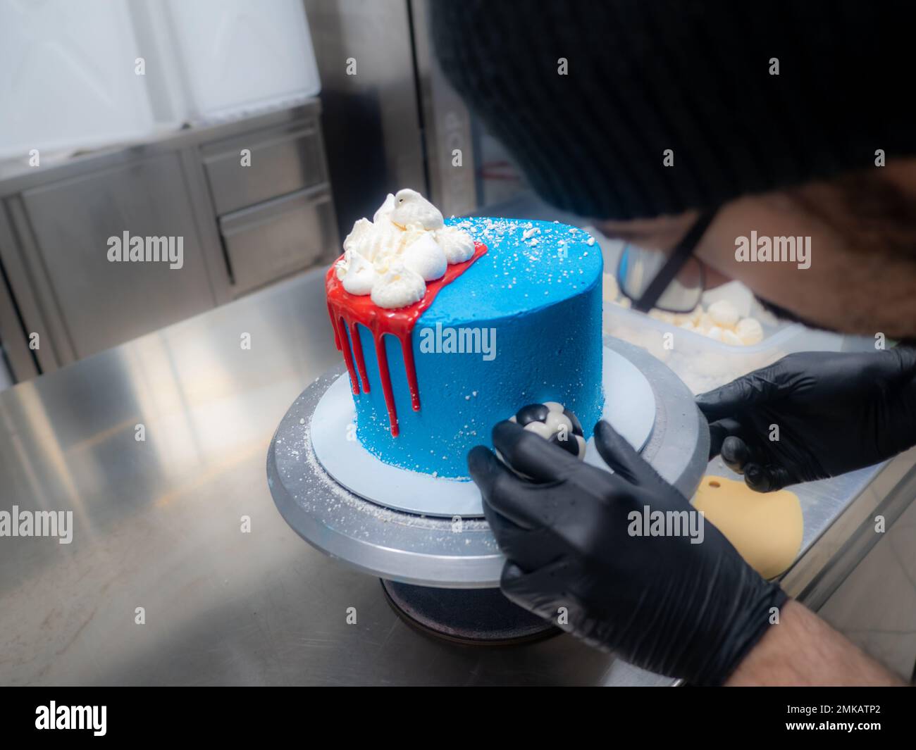 blue sprayed frosted cake on stand dripped with red ganache filling and ...
