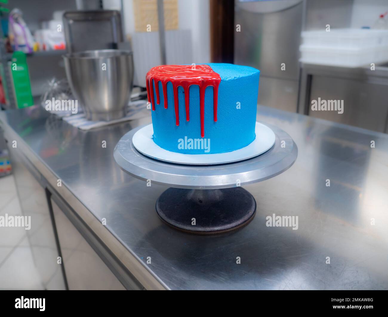blue sprayed frosted cake on stand dripped with red ganache filling and ...