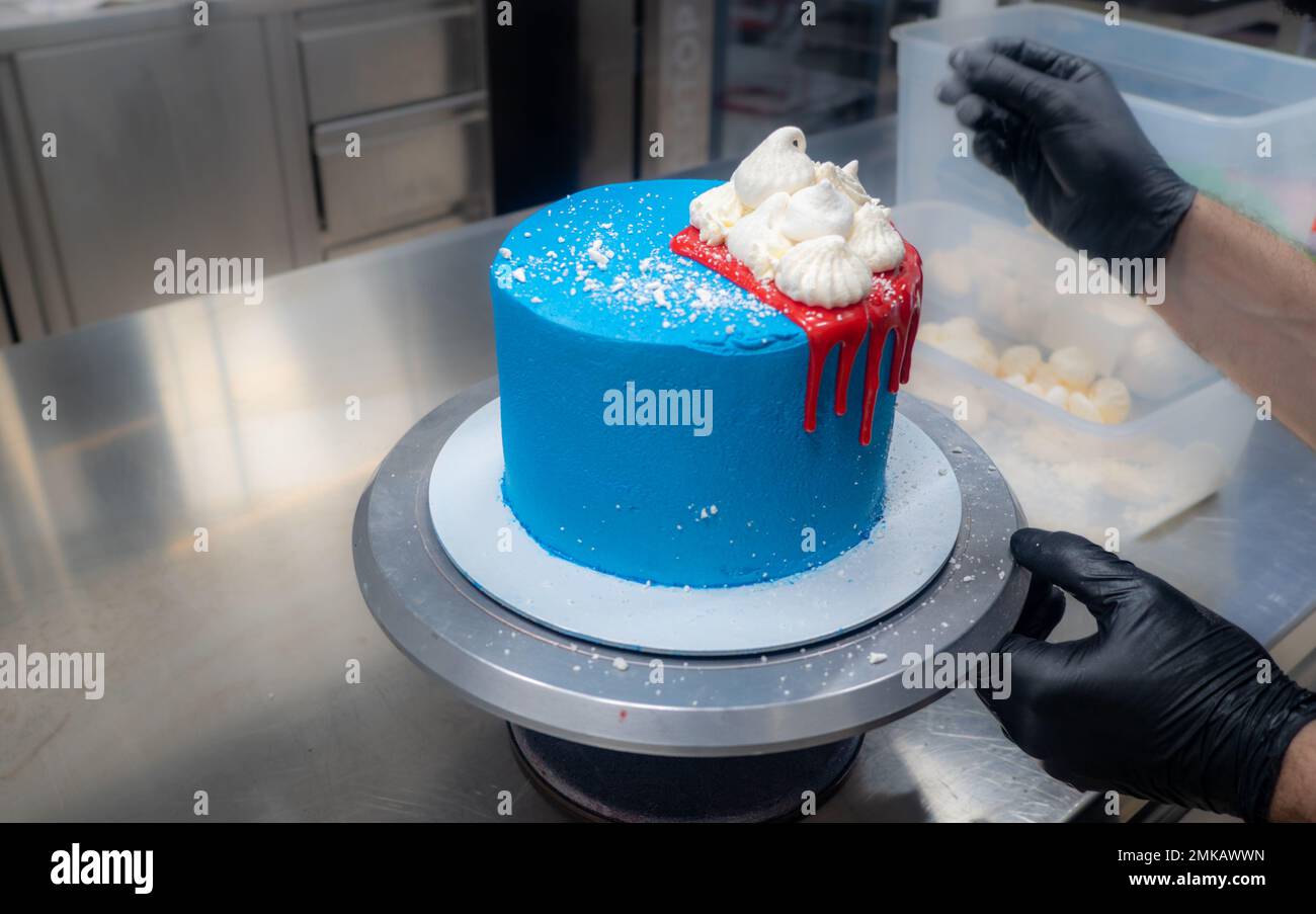 blue sprayed frosted cake on stand dripped with red ganache filling and ...