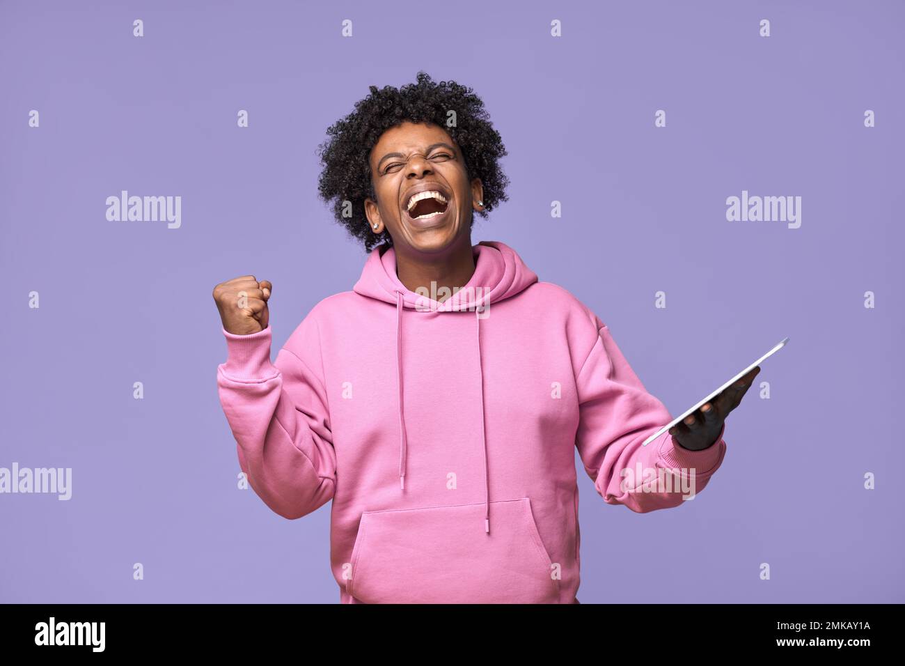 Happy euphoric African teen student winner boy holding tablet ...