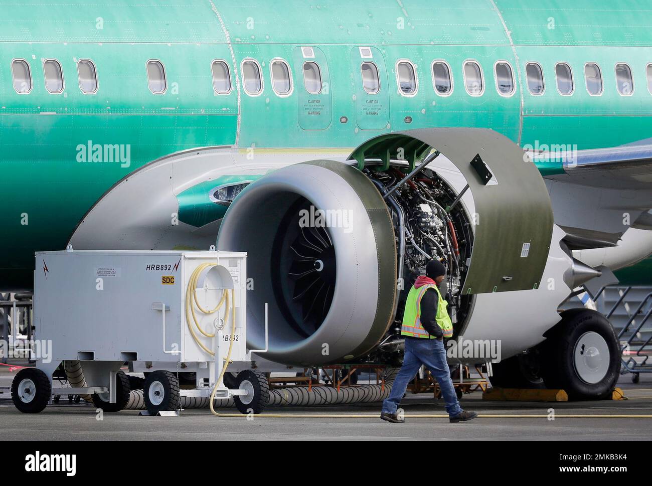 A worker walks past an engine on a Boeing 737 MAX 8 airplane being ...