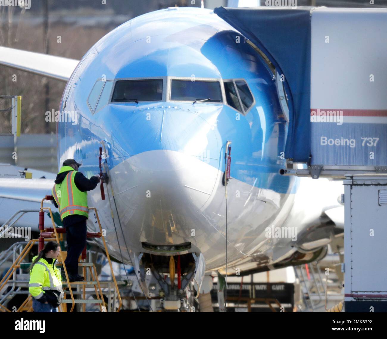 A worker stands on a platform near a Boeing 737 MAX 8 airplane being ...
