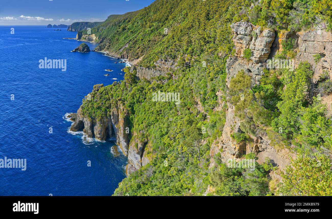 Coastal view of steep sheer cliffs and calm blue ocean at Waterfall Bay ...