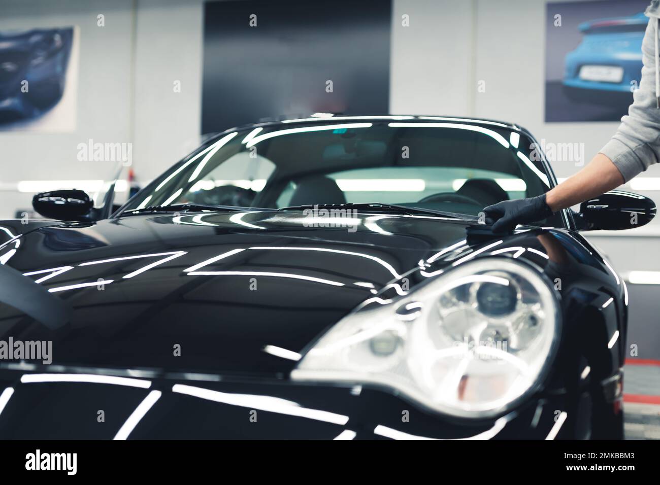 Close-up of the headlights and hood of black car during ceramic coating ...