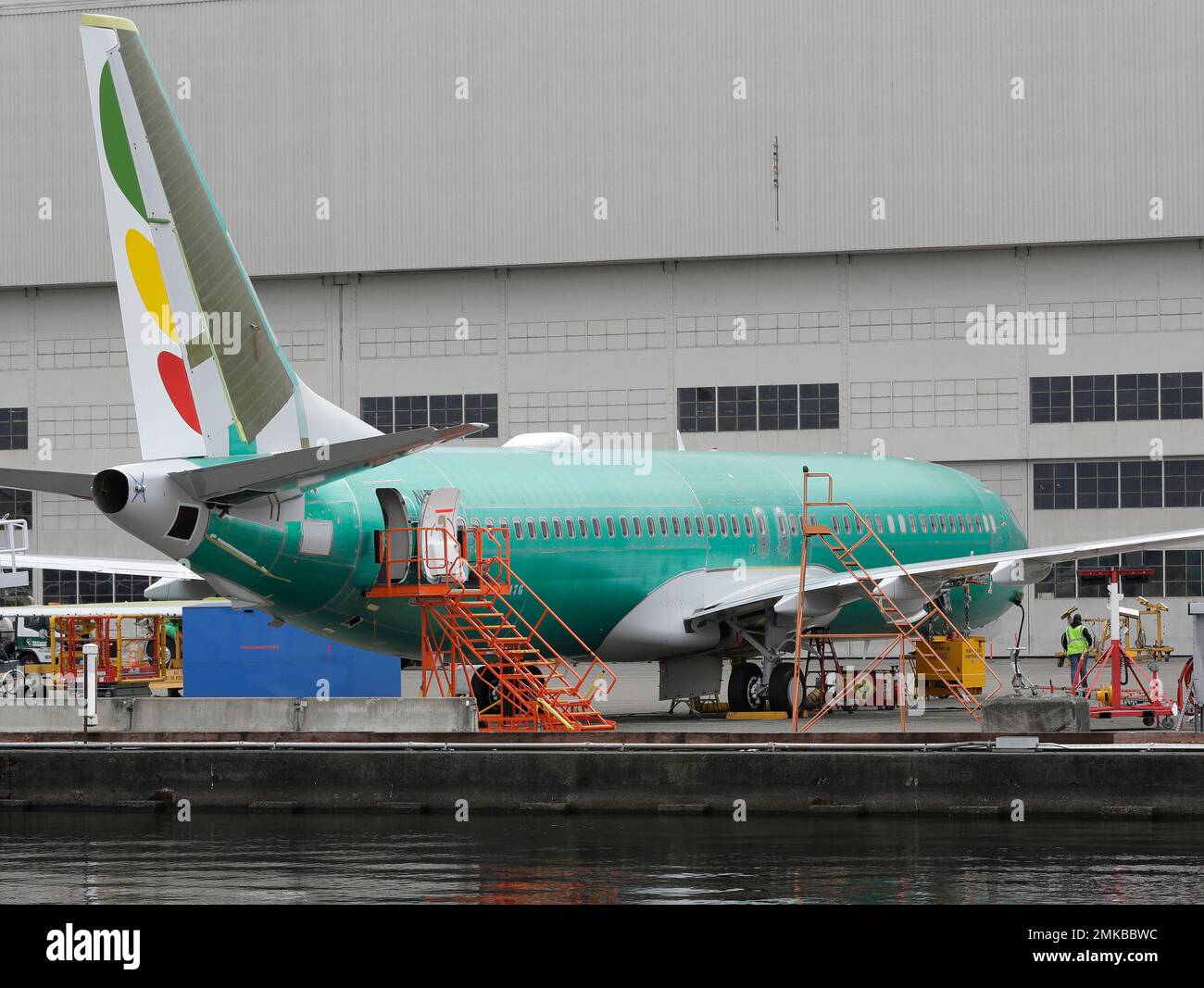 A worker stands near a Boeing 737 MAX 8 airplane parked at Boeing Co.'s ...