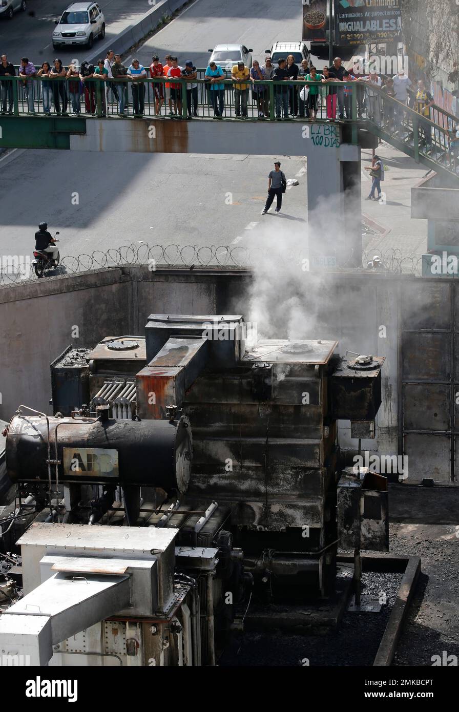 Pedestrians look down at smoldering transformers and electrical ...