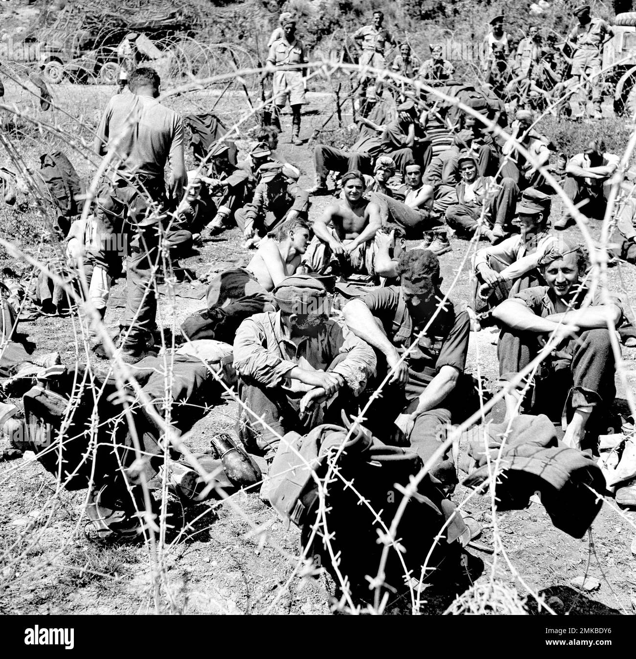 Behind the spiked lace work of a barbed wire compound, German soldiers ...