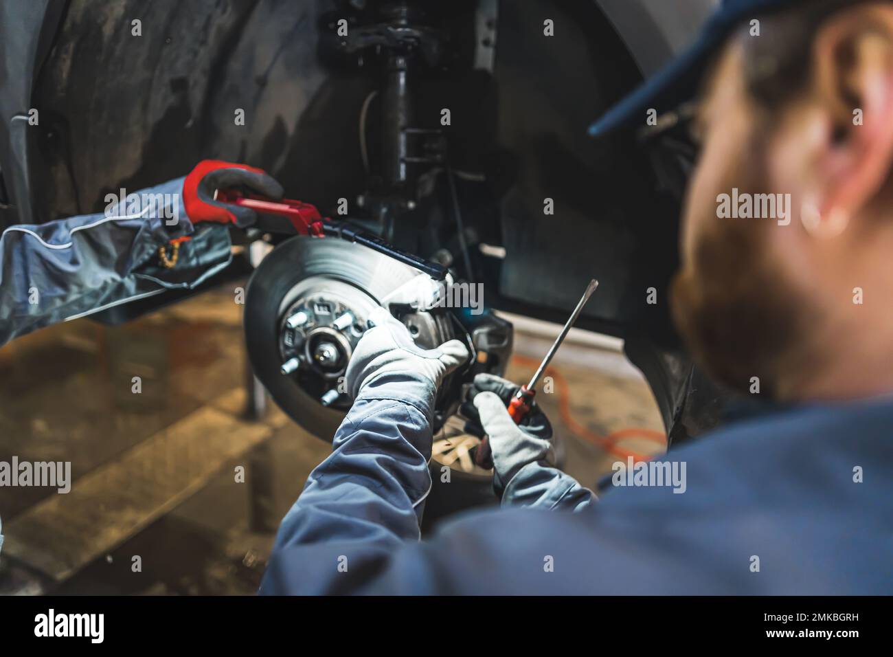 Mechanic fixing car tyres using a screwdriver and tools in an auto ...