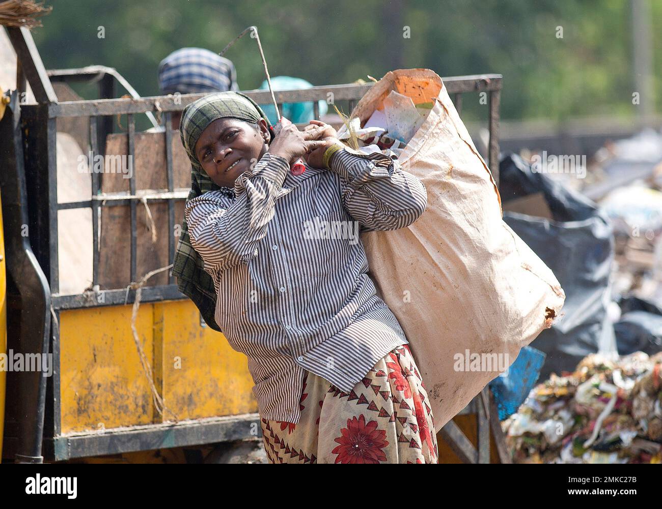 An Indian ragpicker woman walks with recyclable material from a dump ...