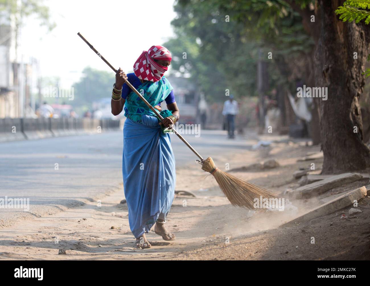 An Indian municipal worker sweeps a street on International Women's Day ...