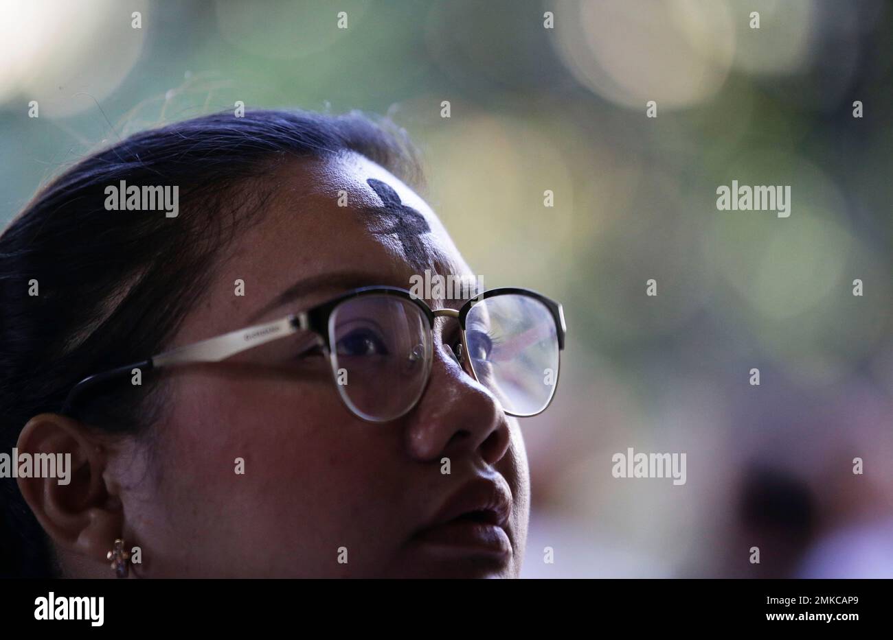 A Roman Catholic devotee with a cross symbol on her forehead attends a ...