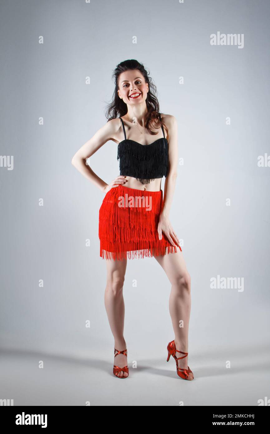 An elegant dancer performs a Latin American dance in an elegant red ...