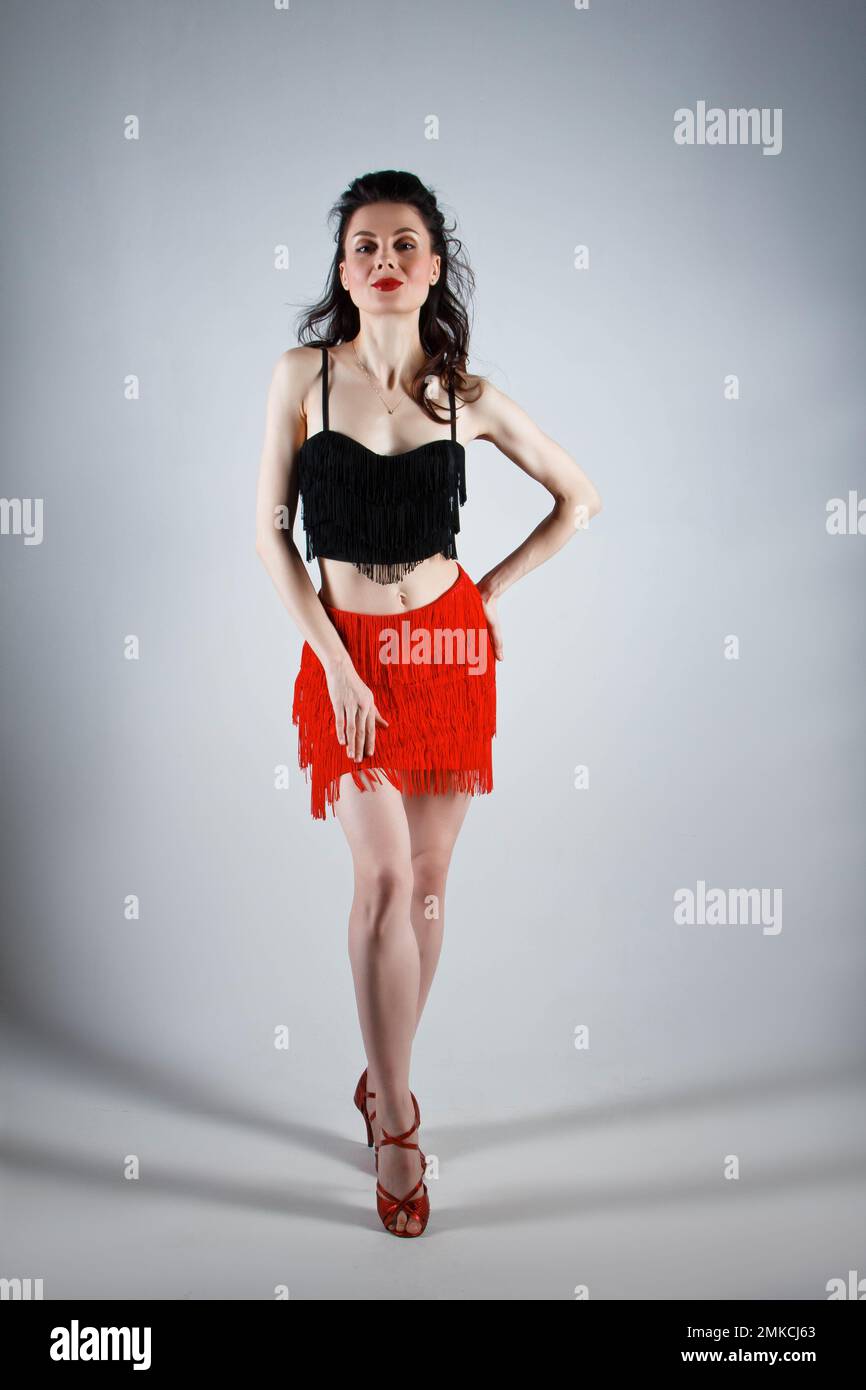 An elegant dancer performs a Latin American dance in an elegant red ...