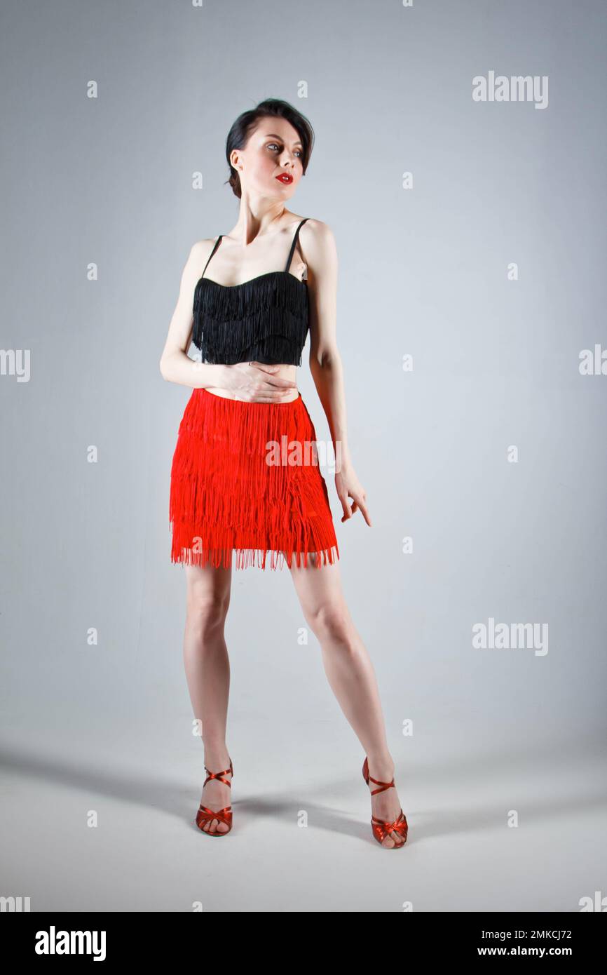 An elegant dancer performs a Latin American dance in an elegant red ...
