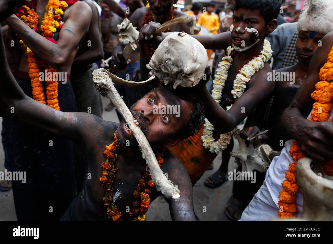An Indian devotee holds a skull and a bone as he dances during a ...