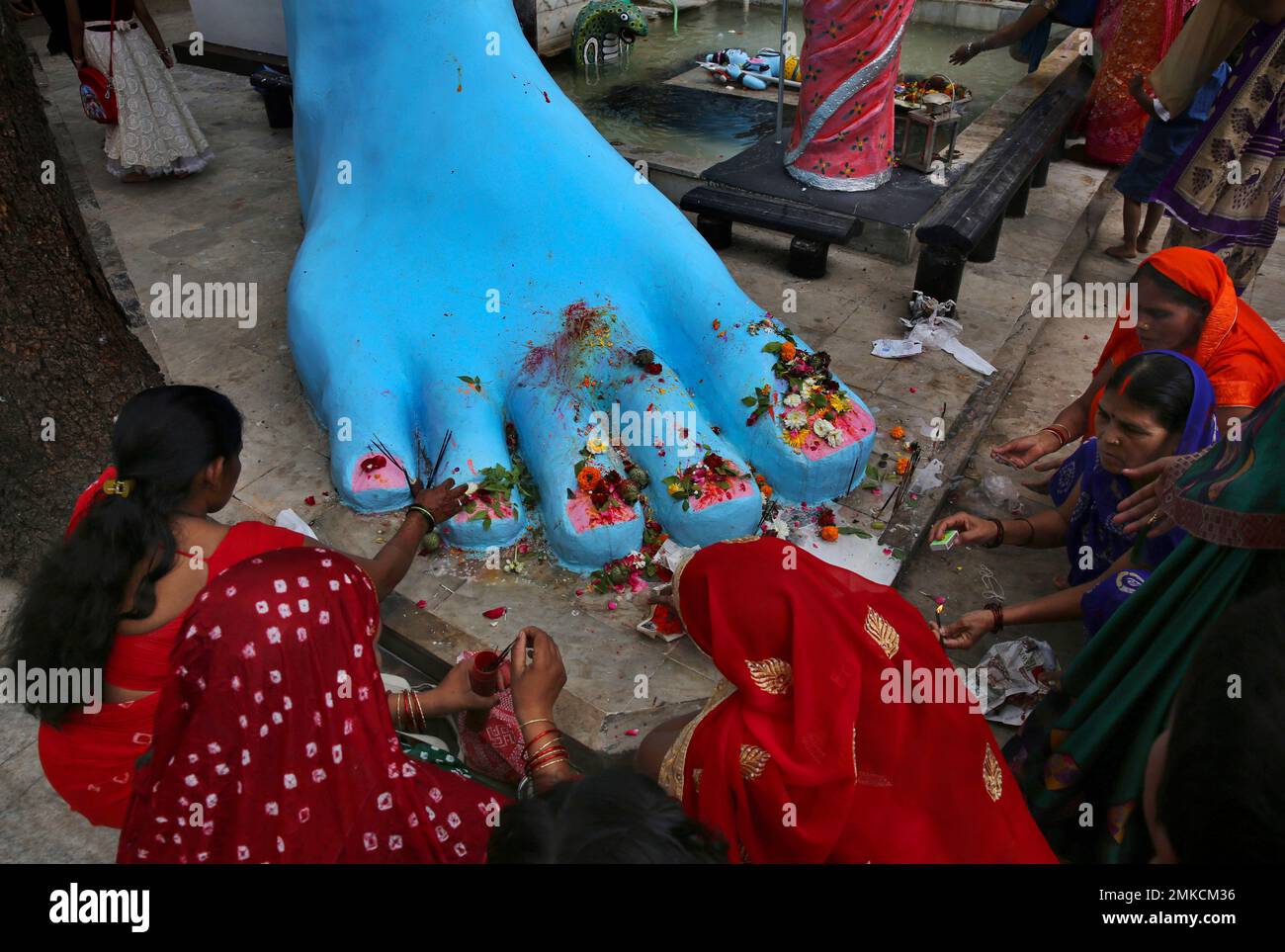 Indian Hindu devotees pray at the foot of a huge statue of Lord Shiva ...
