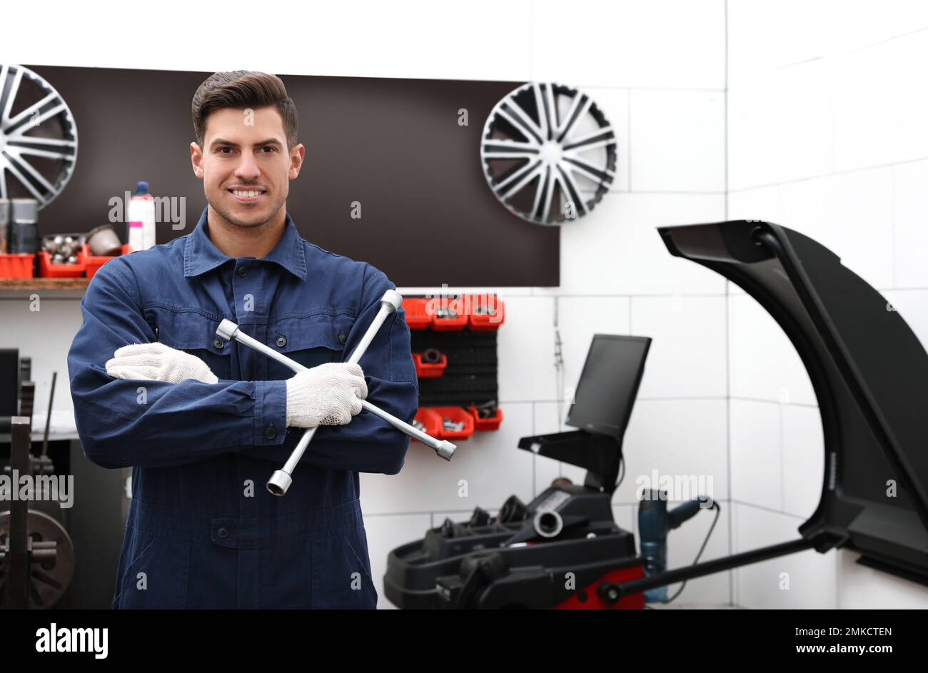 Professional worker with wheel wrench in shop of modern tire service ...