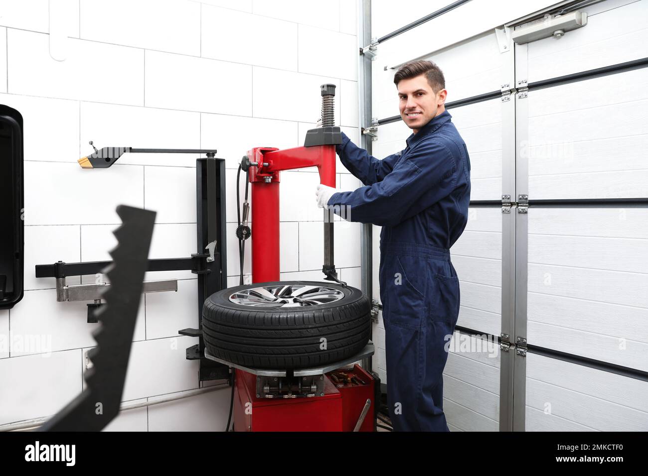 Man working with tire fitting machine at car service Stock Photo - Alamy