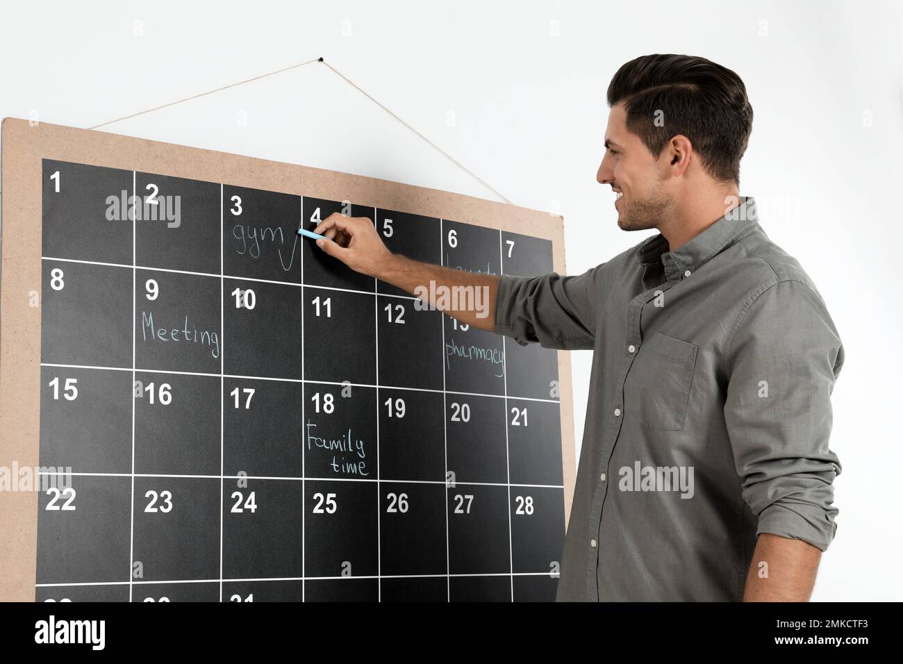 Handsome man writing with chalk on board calendar Stock Photo - Alamy
