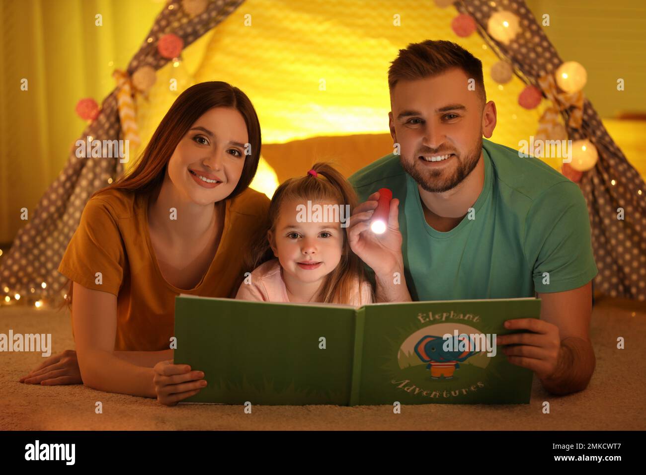 Family with flashlight reading book at home Stock Photo - Alamy