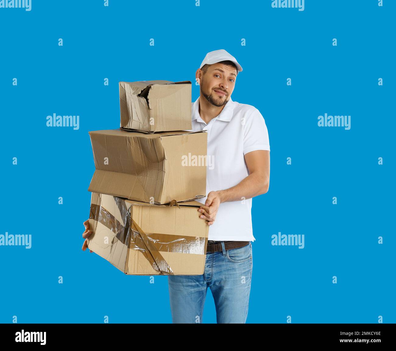 Emotional courier with damaged cardboard boxes on blue background. Poor ...