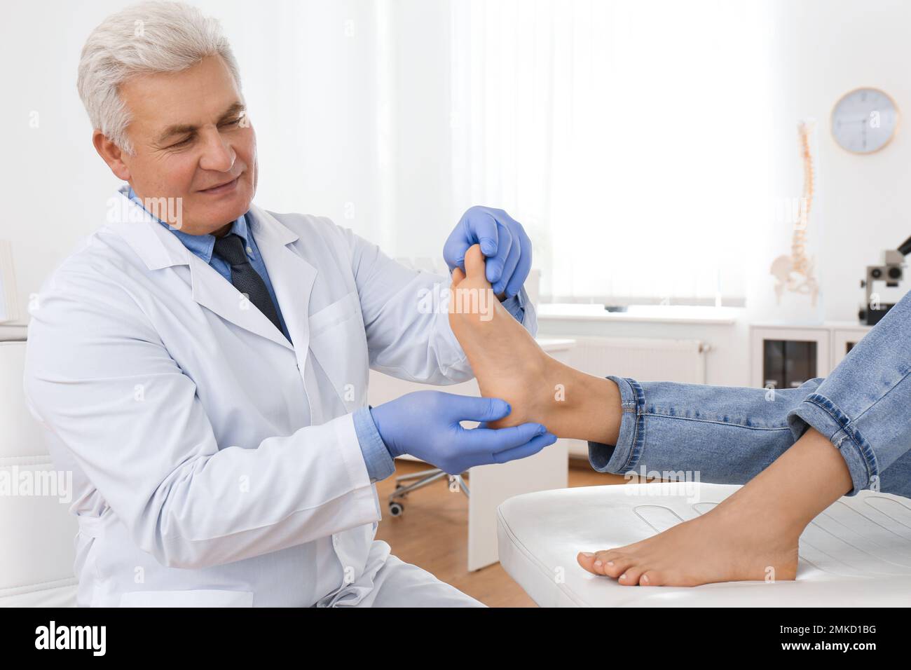 Male orthopedist checking patient's foot in clinic Stock Photo - Alamy