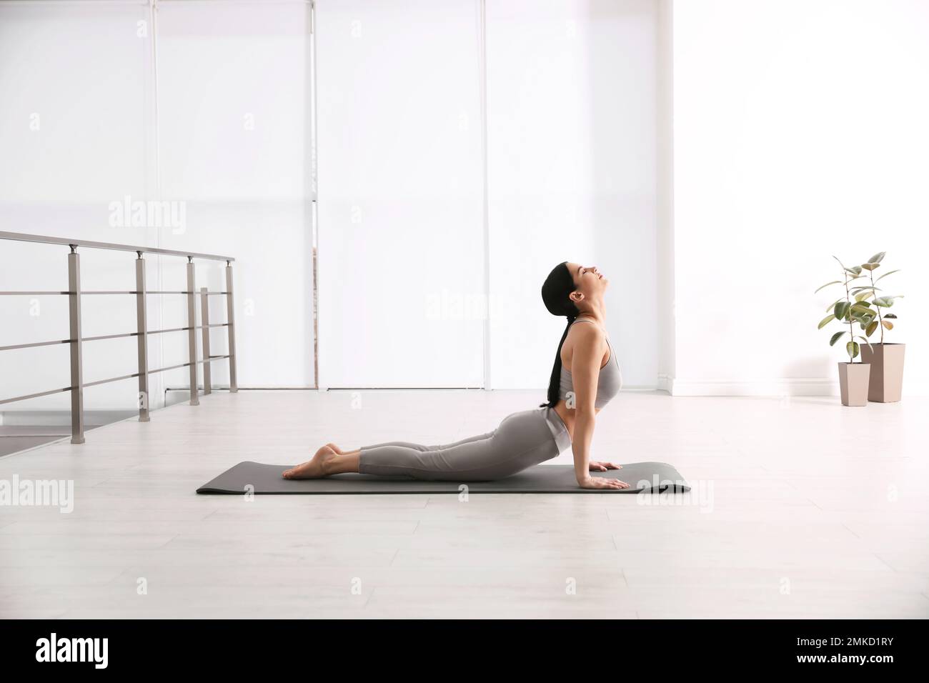Young woman practicing cobra asana in yoga studio. Bhujangasana pose ...