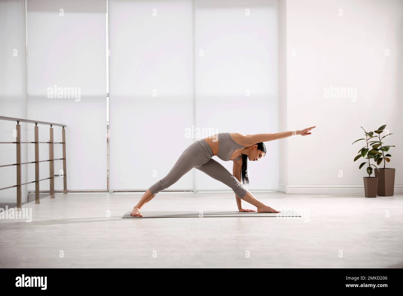 Young woman practicing triangle asana in yoga studio. Utthita ...