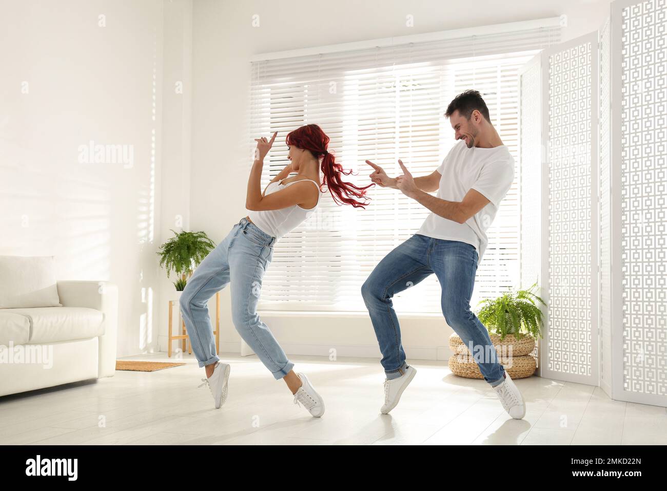 Beautiful young couple dancing in living room Stock Photo - Alamy