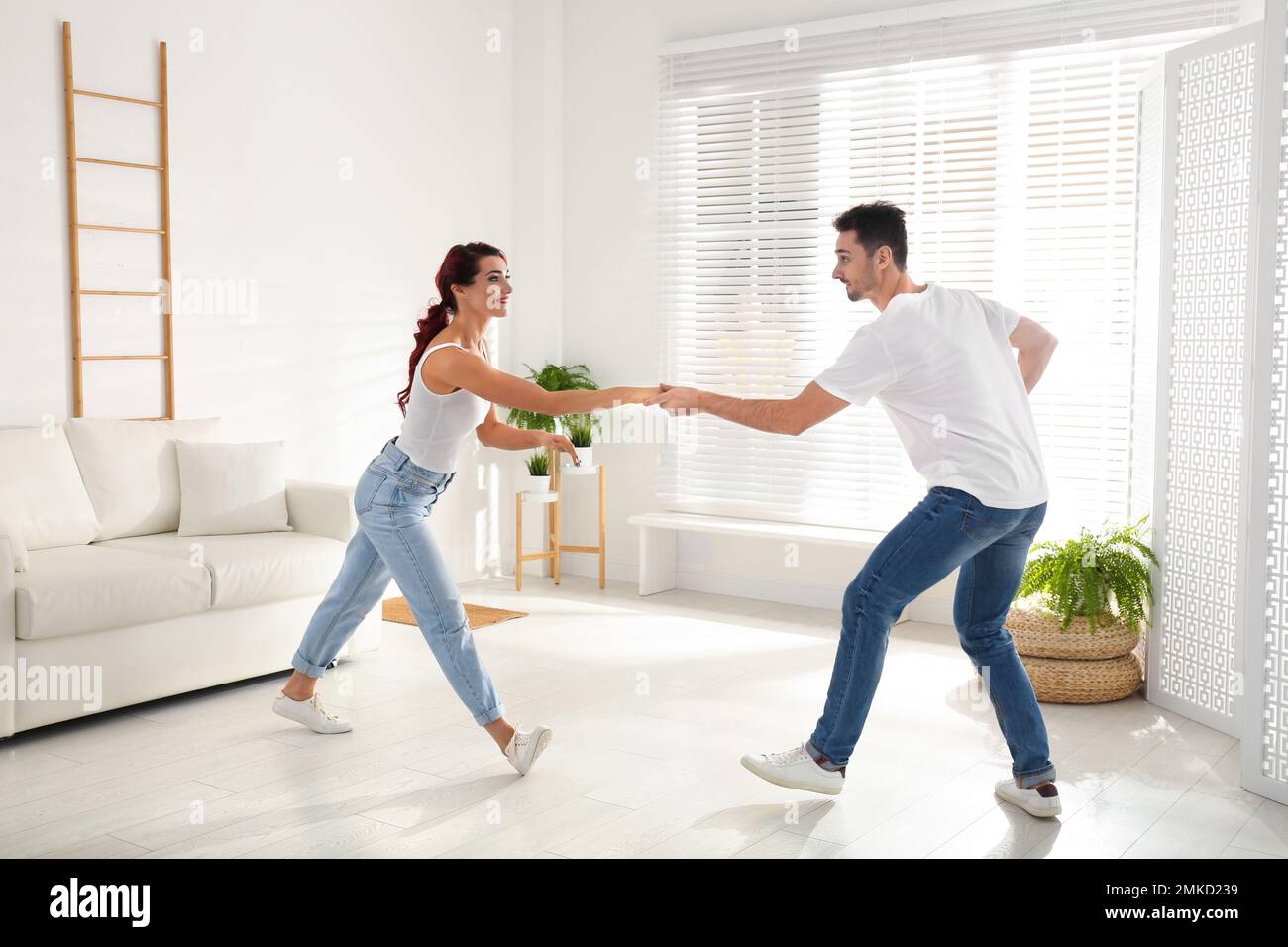 Beautiful young couple dancing in living room Stock Photo - Alamy