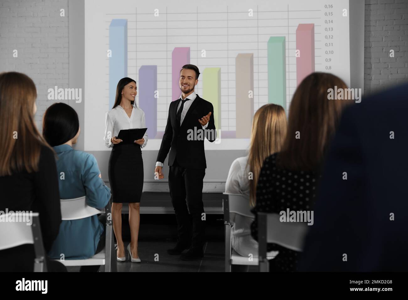 Business trainers giving lecture in conference room with projection ...
