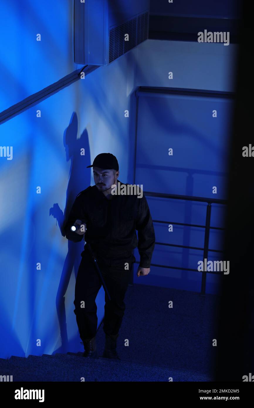Male security guard with flashlight going up stairs in darkness Stock ...
