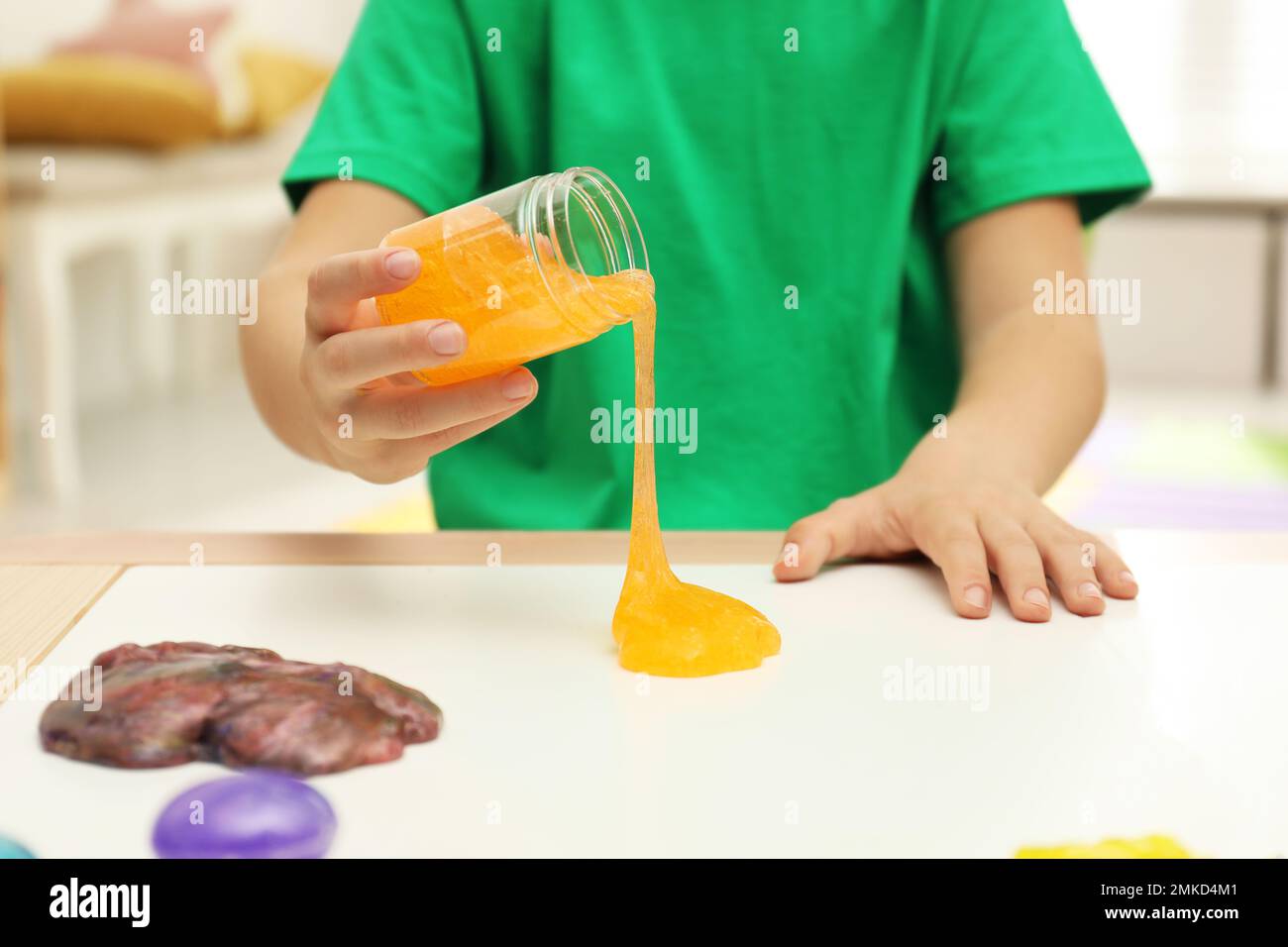 Little boy pouring slime onto table indoors, closeup Stock Photo - Alamy