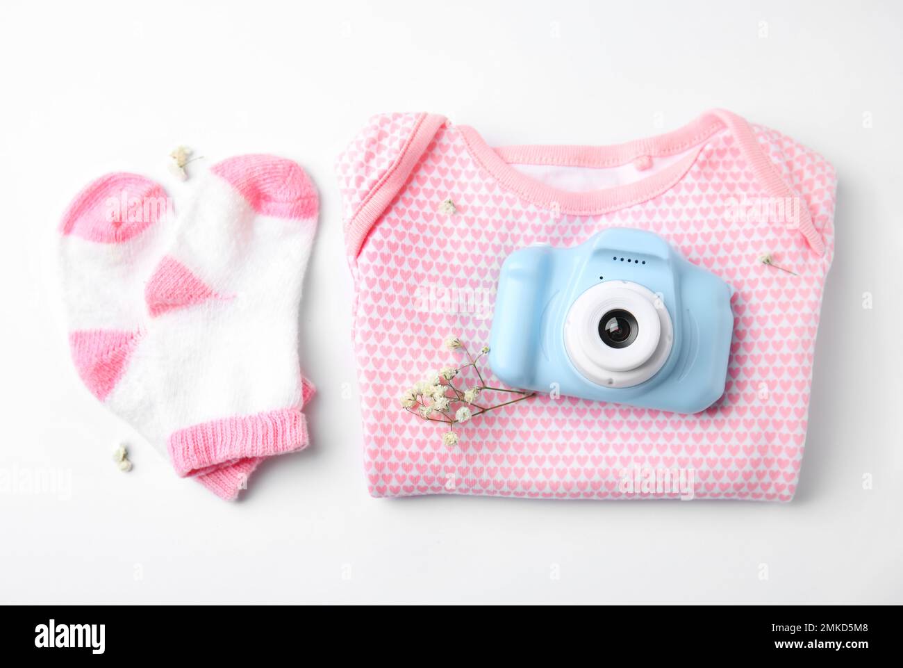 Composition with toy camera and children's clothes on white background ...