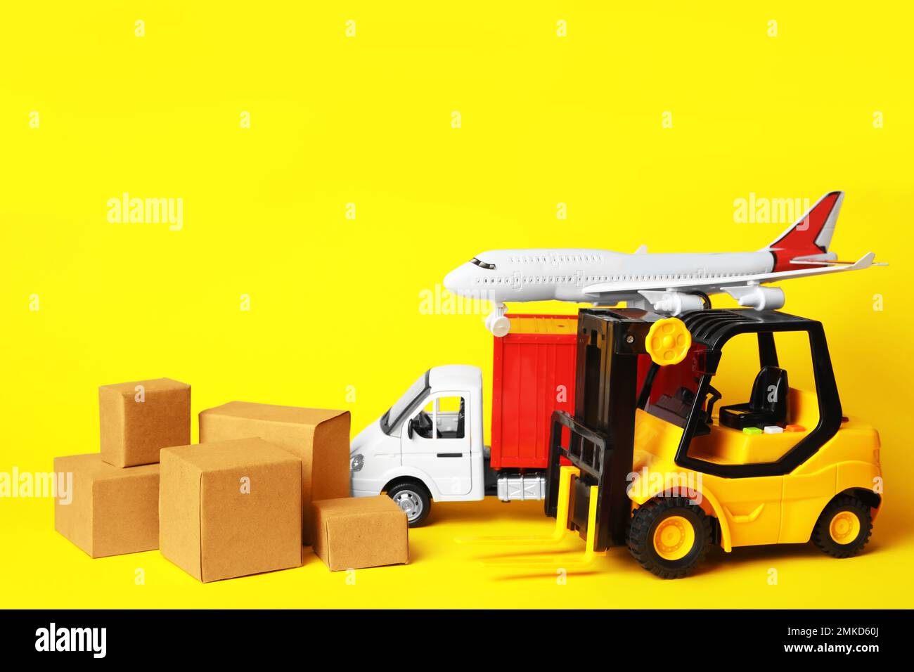 Different toy vehicles with boxes on yellow background. Logistics and ...