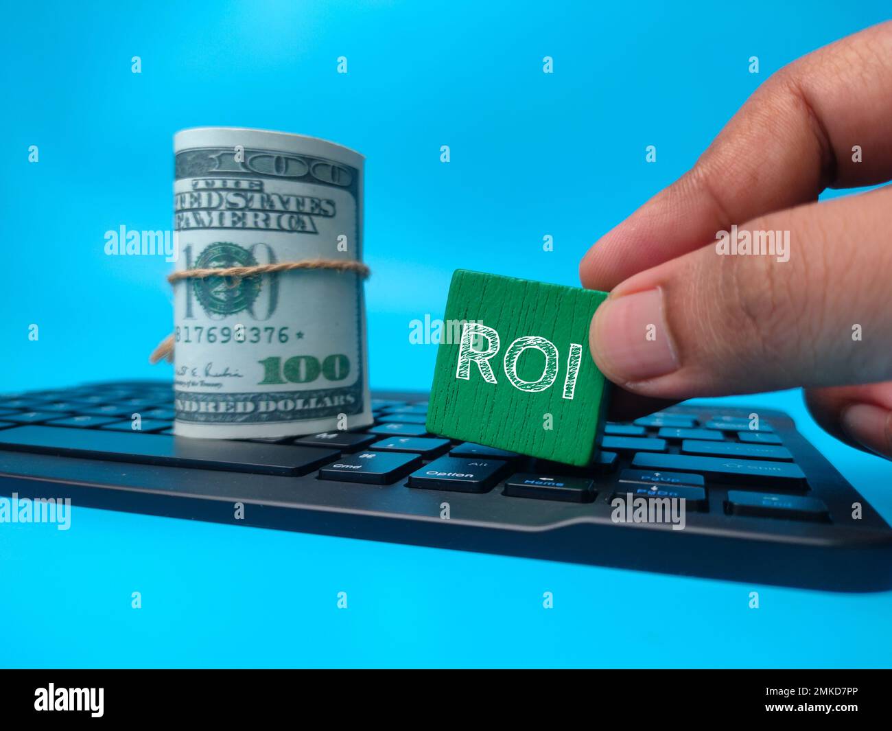 Hand holding colored block with word ROI on a blue background. Business ...