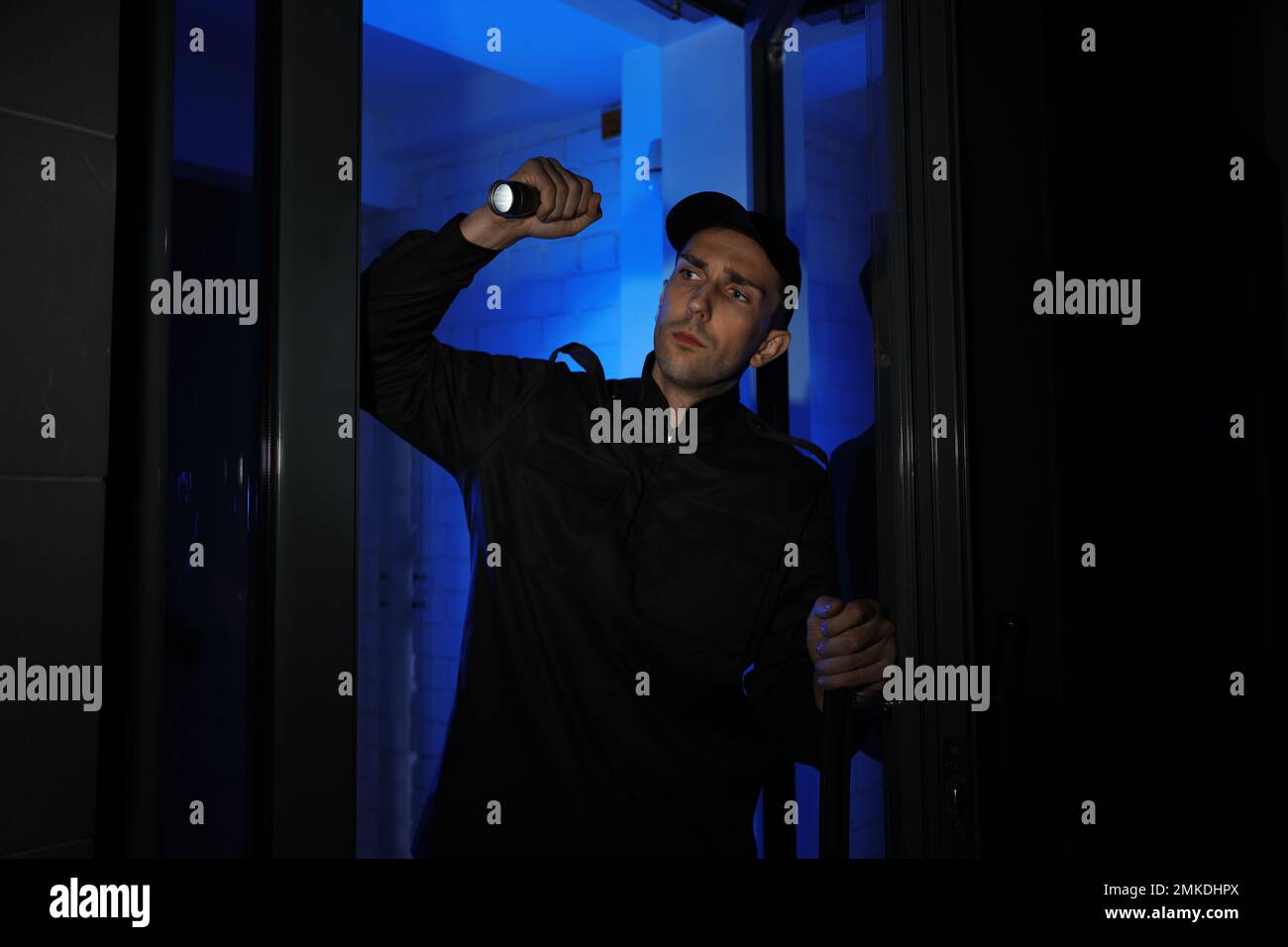 Male security guard with flashlight near entrance door at night Stock ...