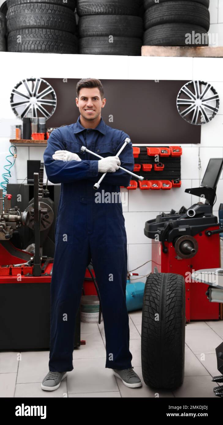 Professional worker with wheel and wrench in shop of modern tire ...