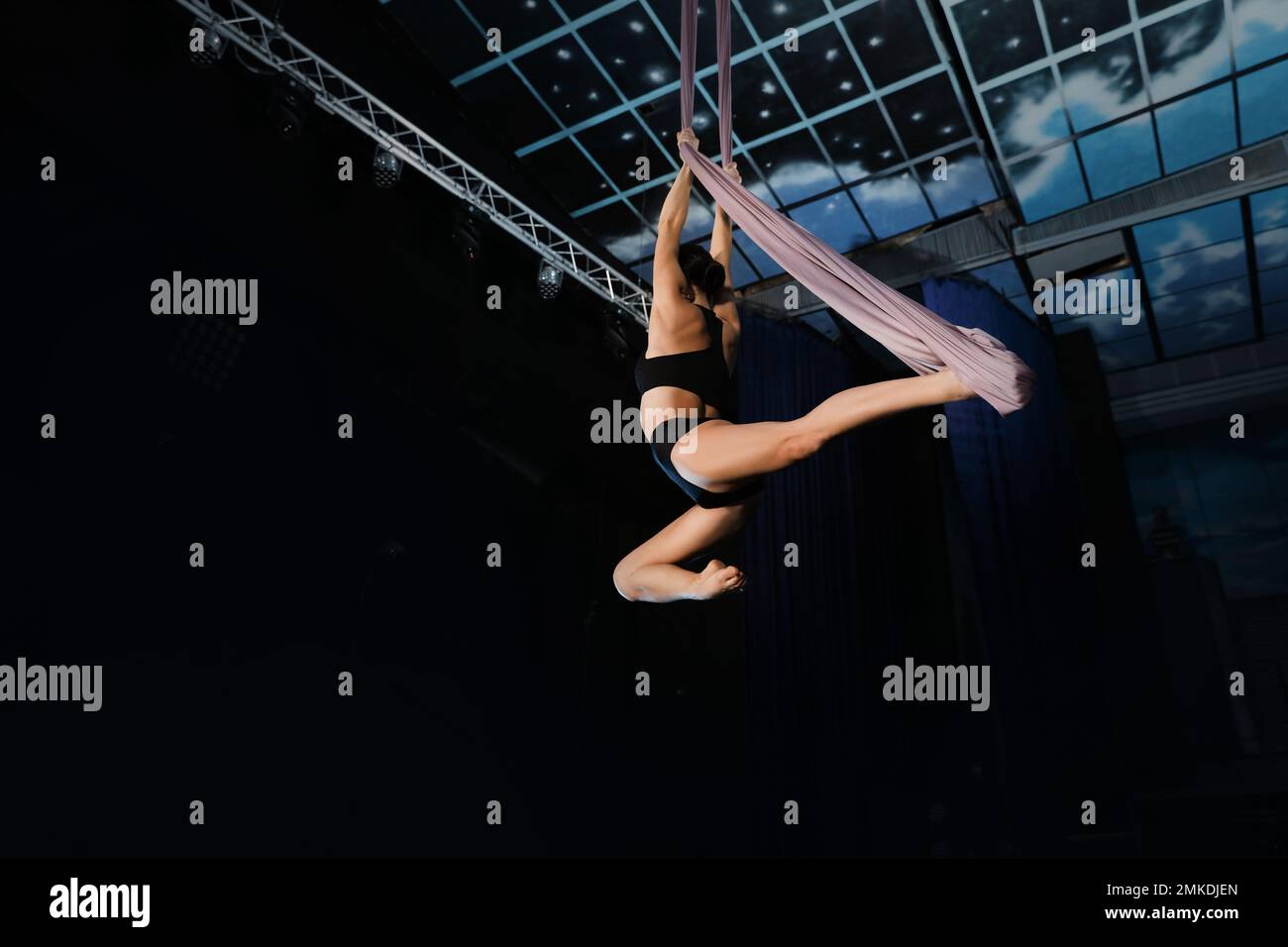 Young woman performing acrobatic element on aerial silk indoors Stock ...