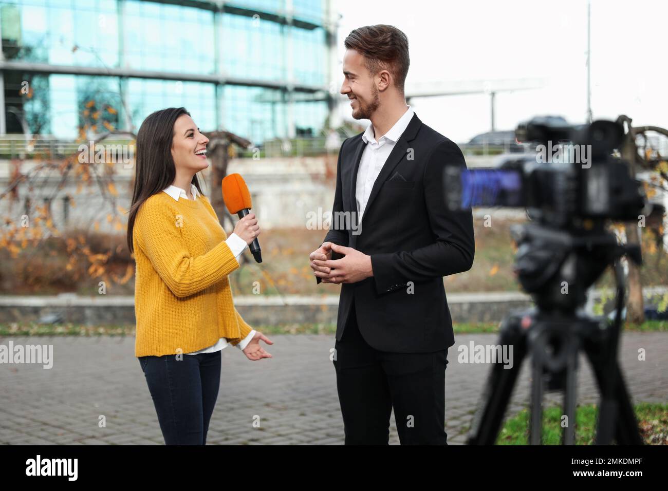 Young journalist interviewing businessman on city street Stock Photo ...