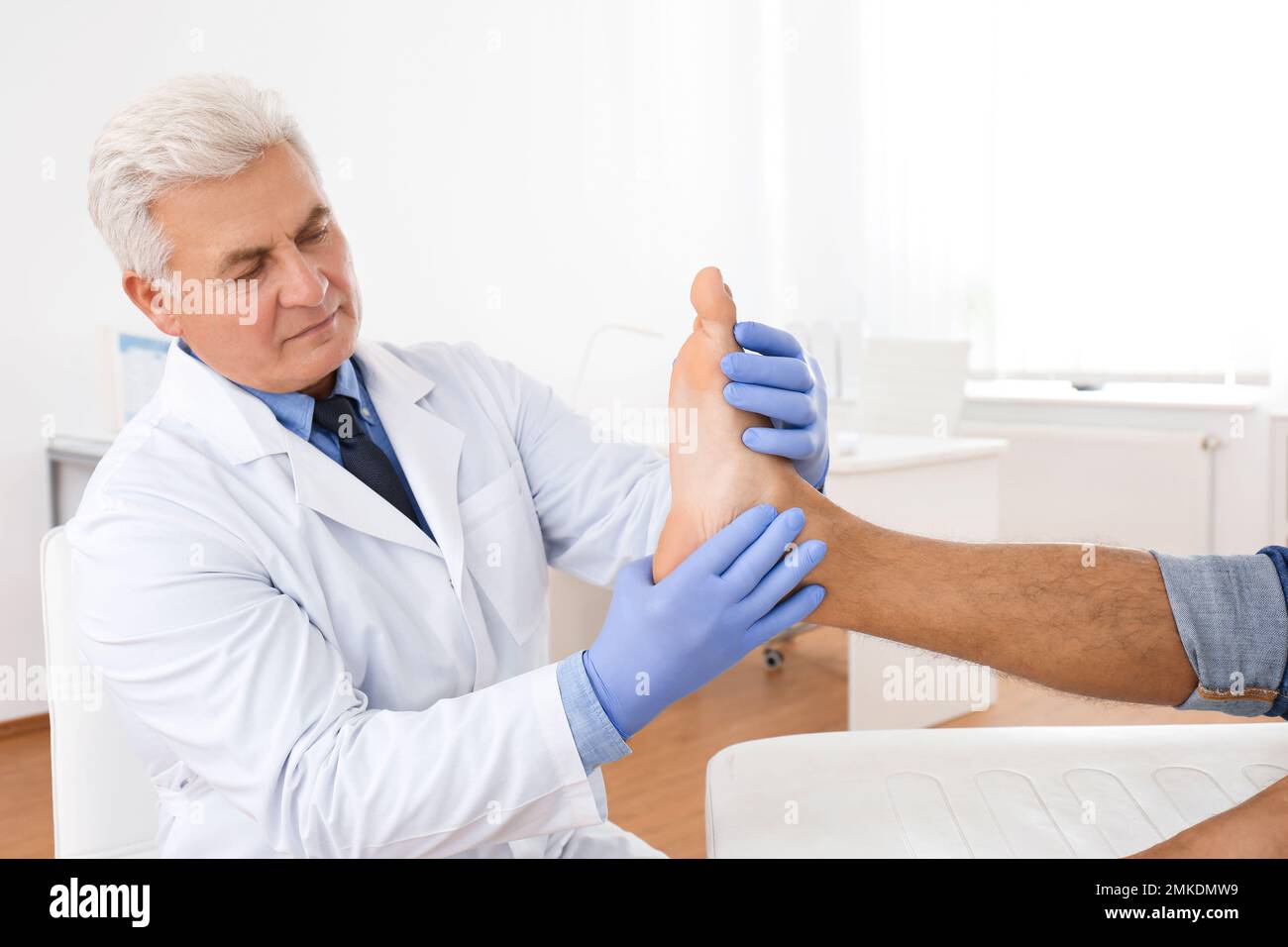 Male orthopedist checking patient's foot in clinic Stock Photo - Alamy