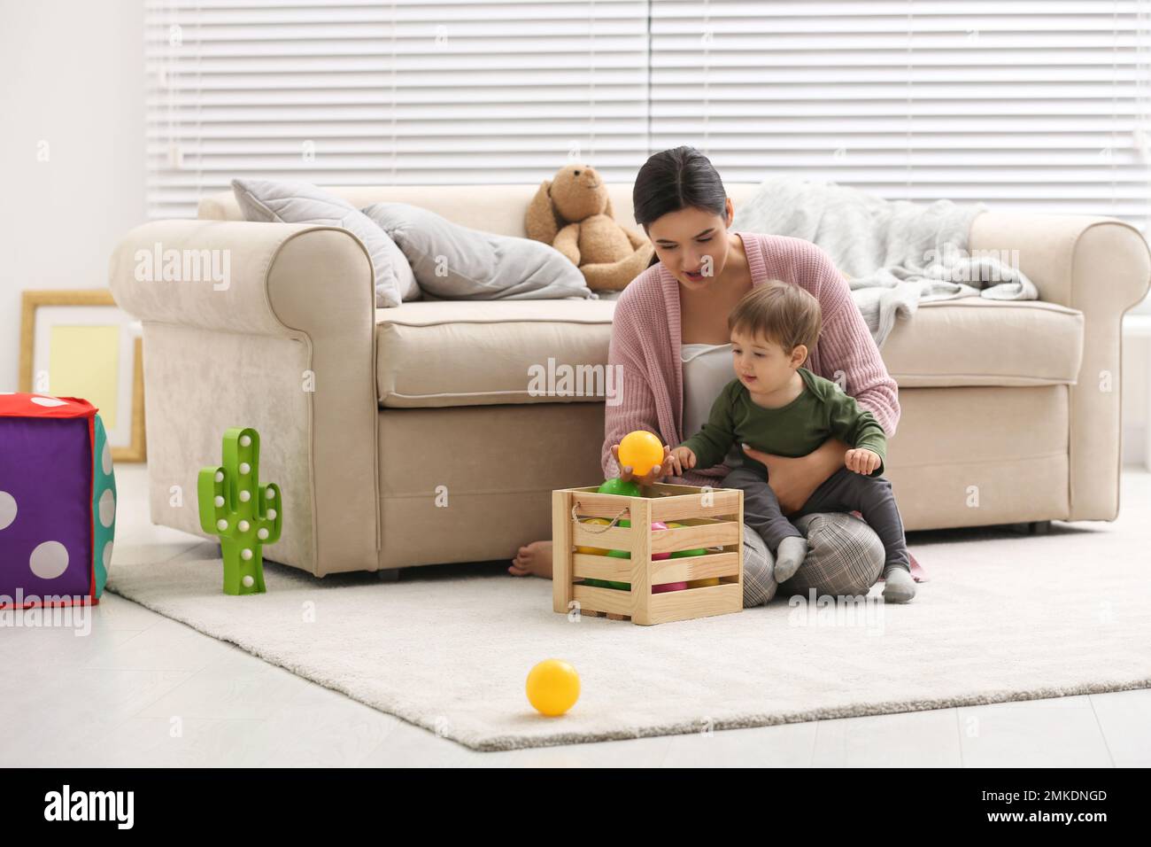 Young nanny and cute little baby playing with toys at home Stock Photo ...