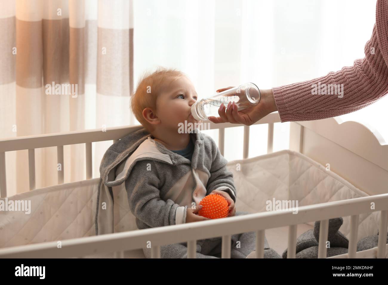 Nanny giving cute little baby water from bottle at home Stock Photo - Alamy