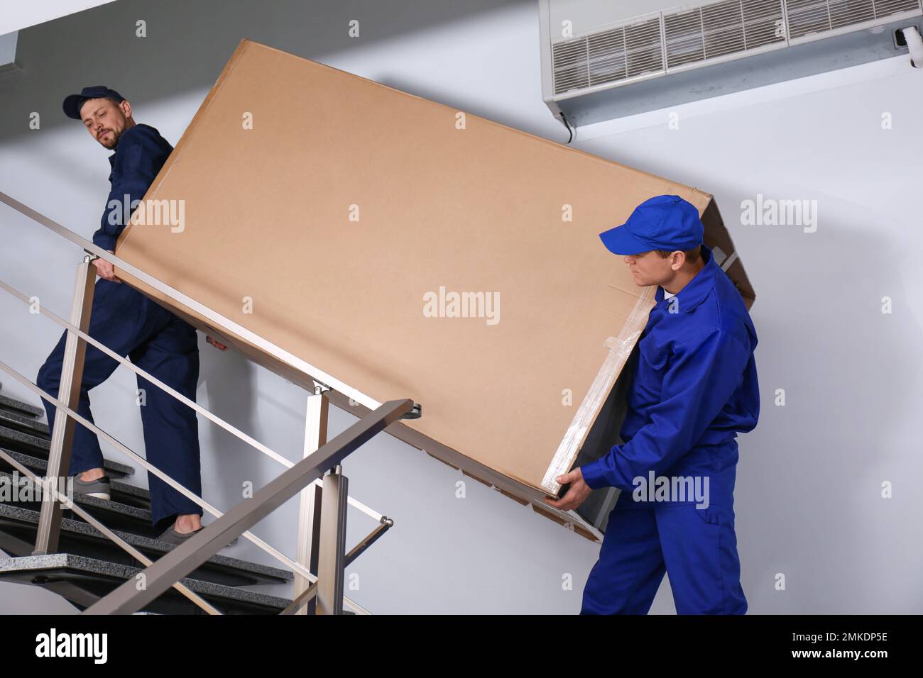 Professional workers carrying refrigerator on stairs indoors Stock ...