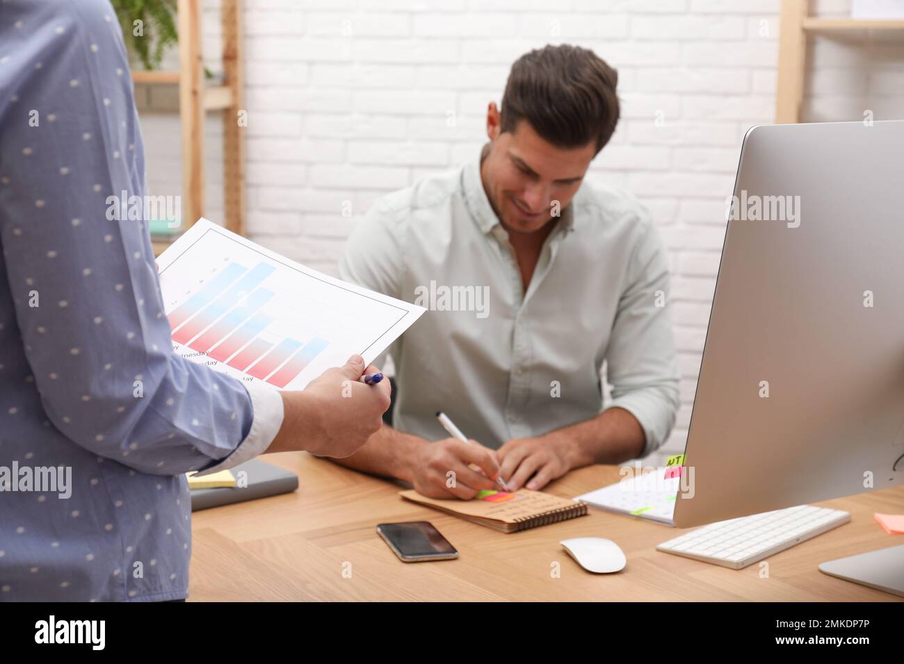 Colleagues making schedule using calendar in office Stock Photo - Alamy