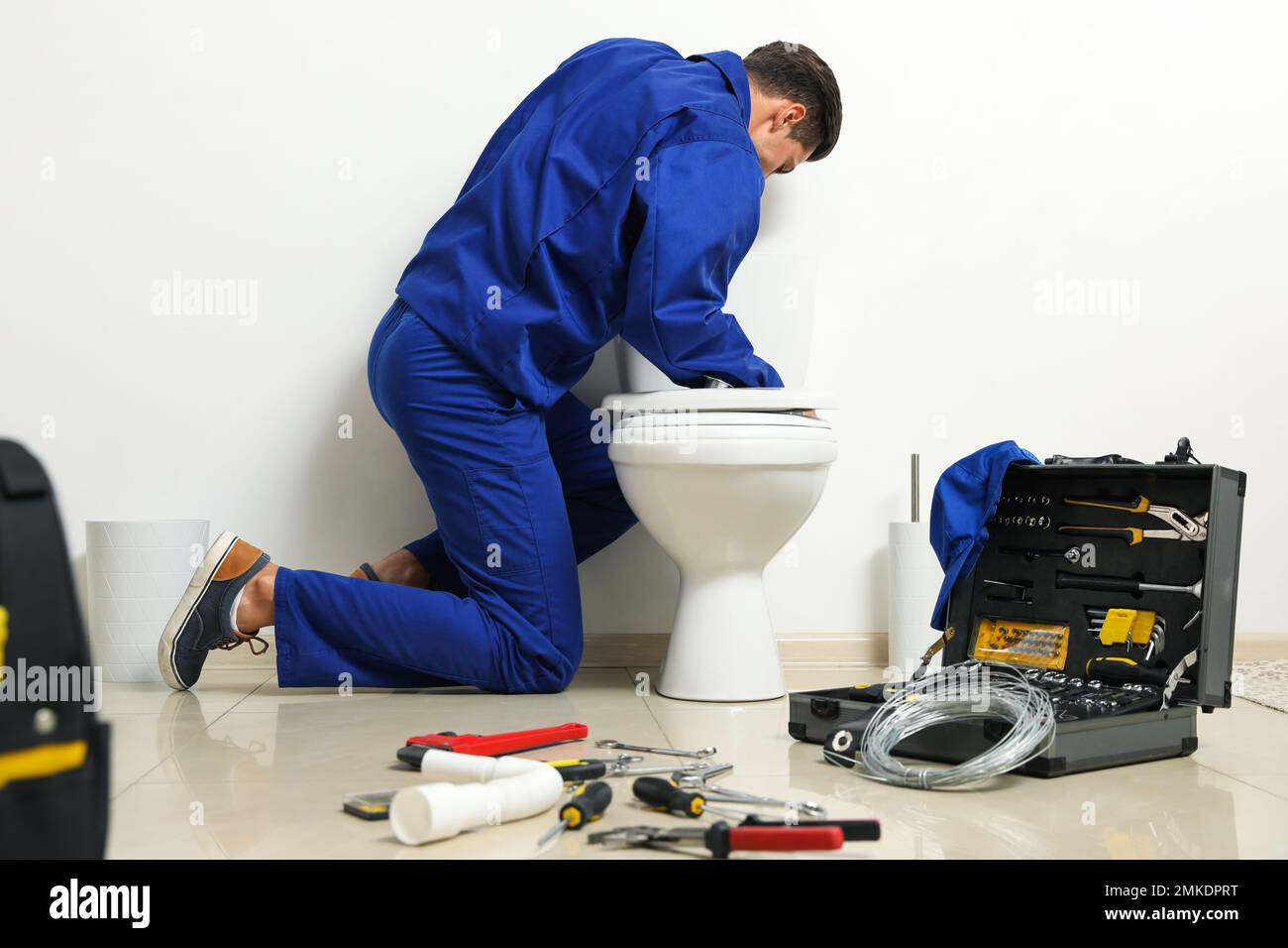 Professional plumber working with toilet bowl in bathroom Stock Photo ...